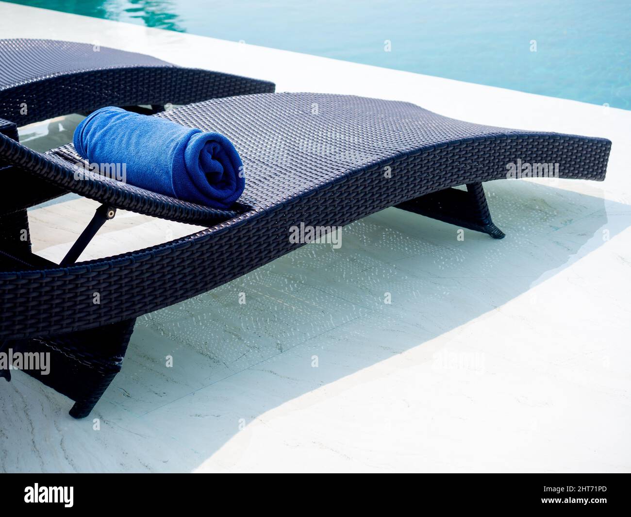 Blue towel pool for the guest rolled on modern rattan sunbed on white ...