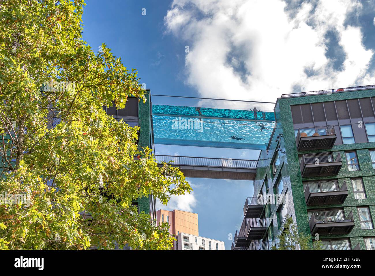 People swimming in The Sky pool, which stretches between two luxury ...