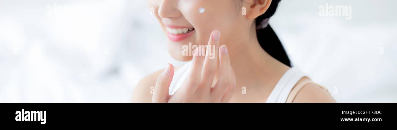 Beautiful young asian woman happy applying cream or lotion with ...