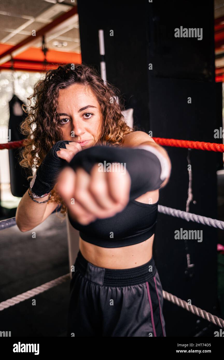 A vertical shot of a curly Caucasian female posing while boxing in the ...