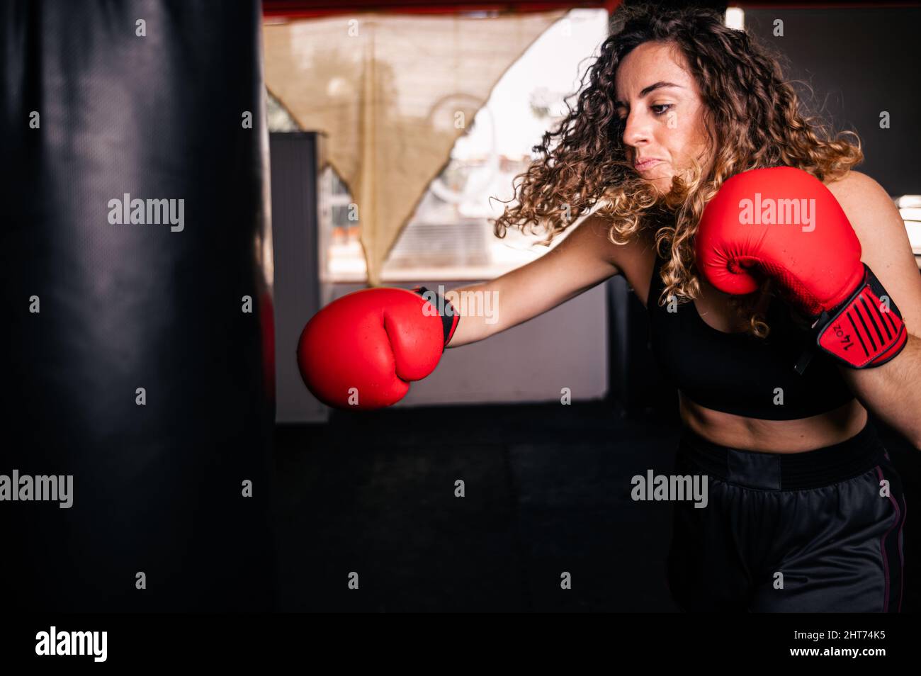Curly brunette Caucasian female practicing boxing in the ring Stock ...