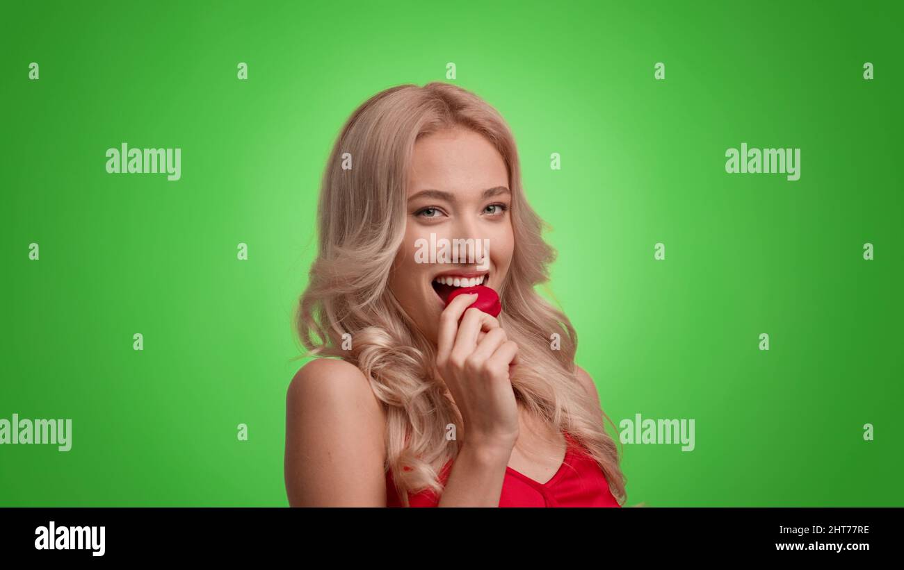 Charming Blonde Lady Eating Macaroon And Winking Eye, Green Background ...