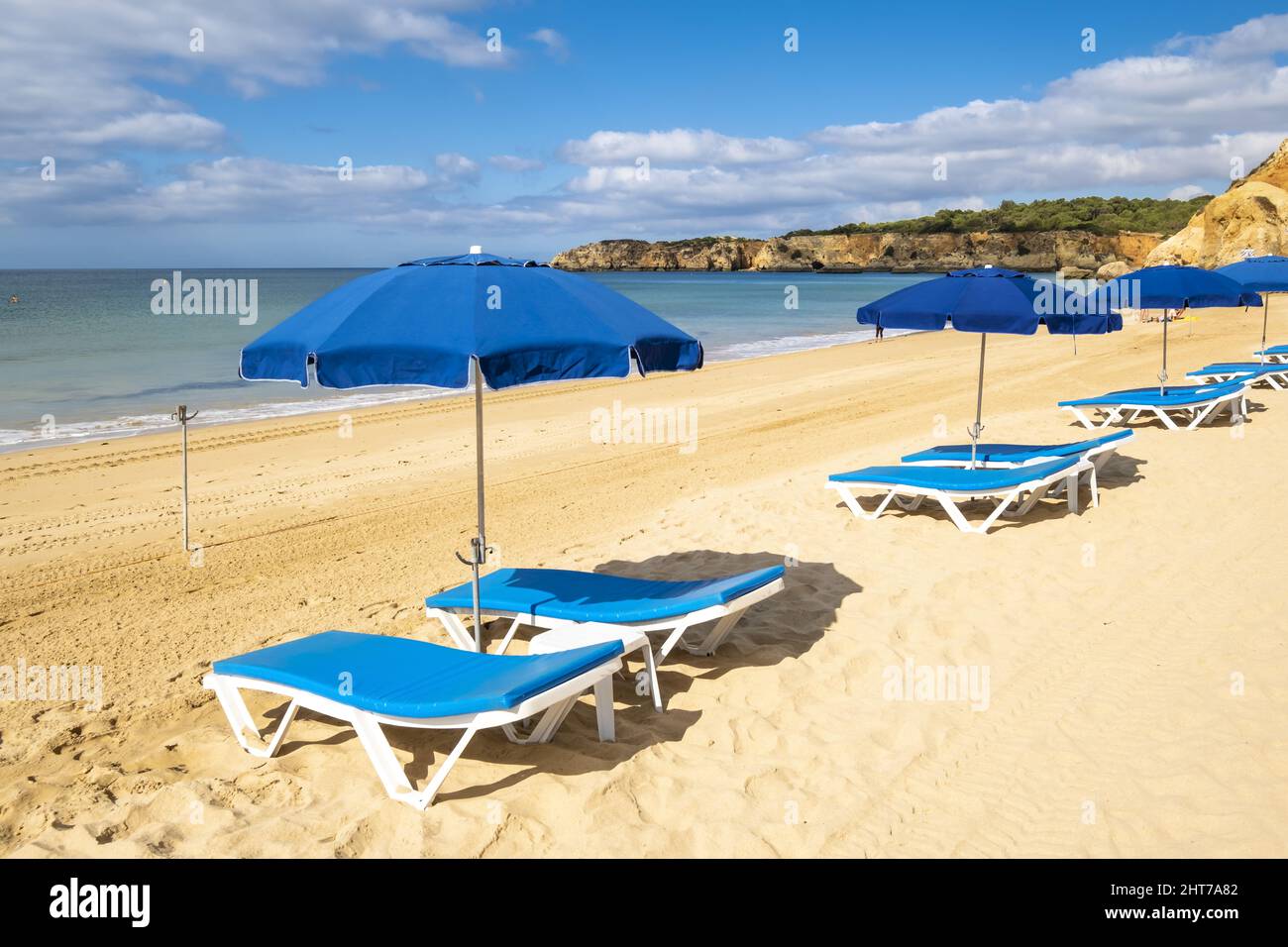 Scenic golden cliffs with umbrella and sunbathing in the Praia do Vau ...