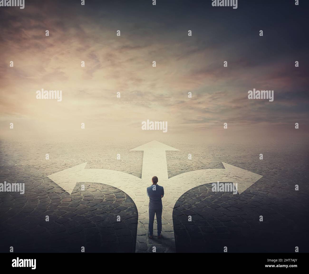 Doubtful businessman stands in front of a crossroad with road split in ...