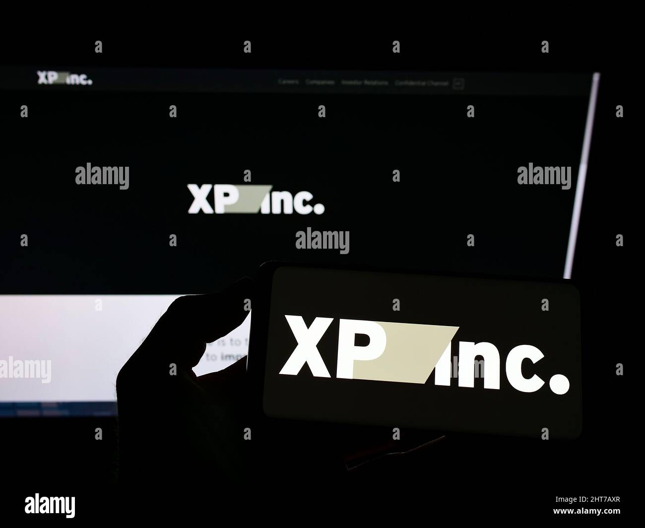 Person holding mobile phone with logo of Brazilian investment company ...