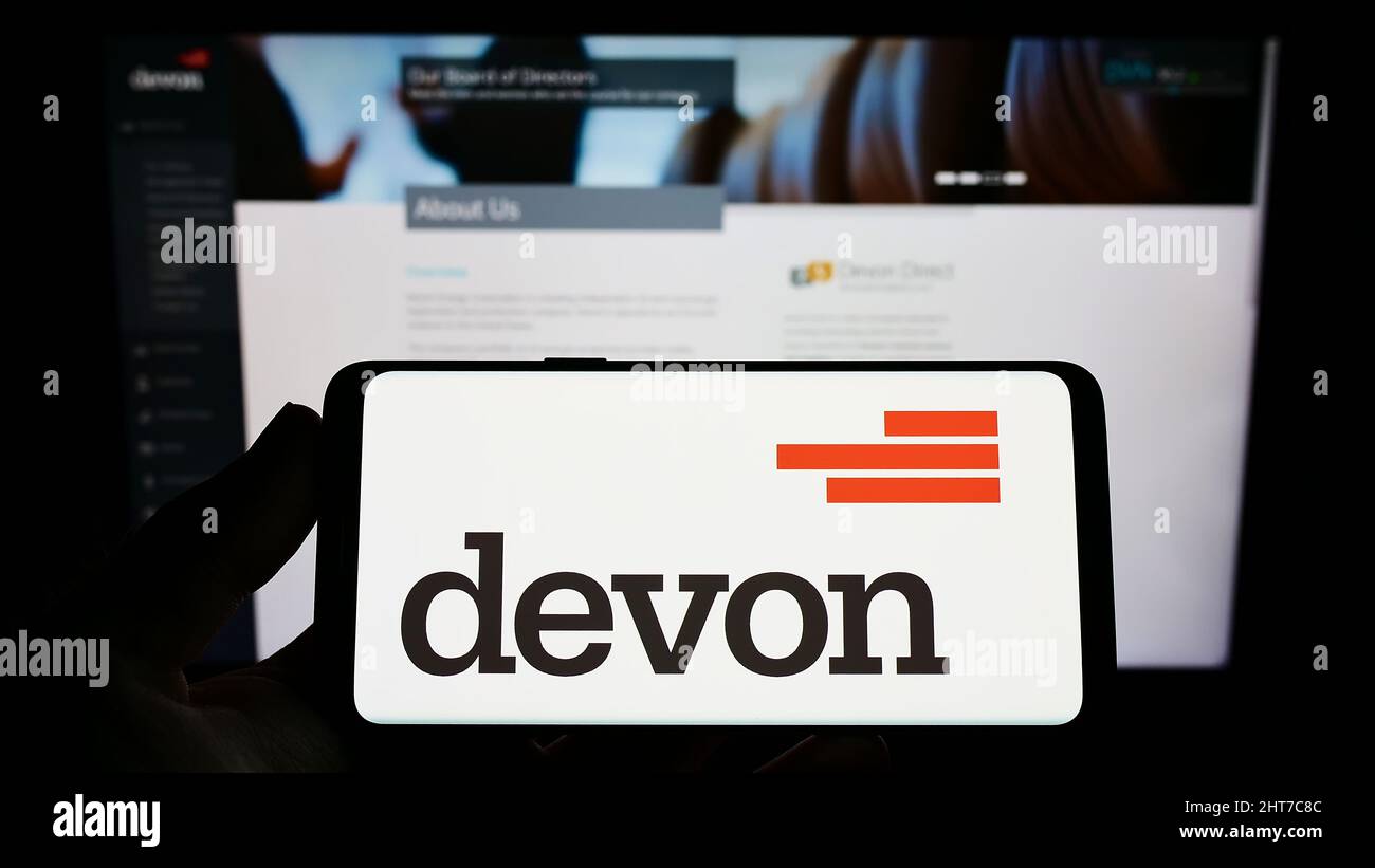 Person holding cellphone with logo of US oil company Devon Energy ...