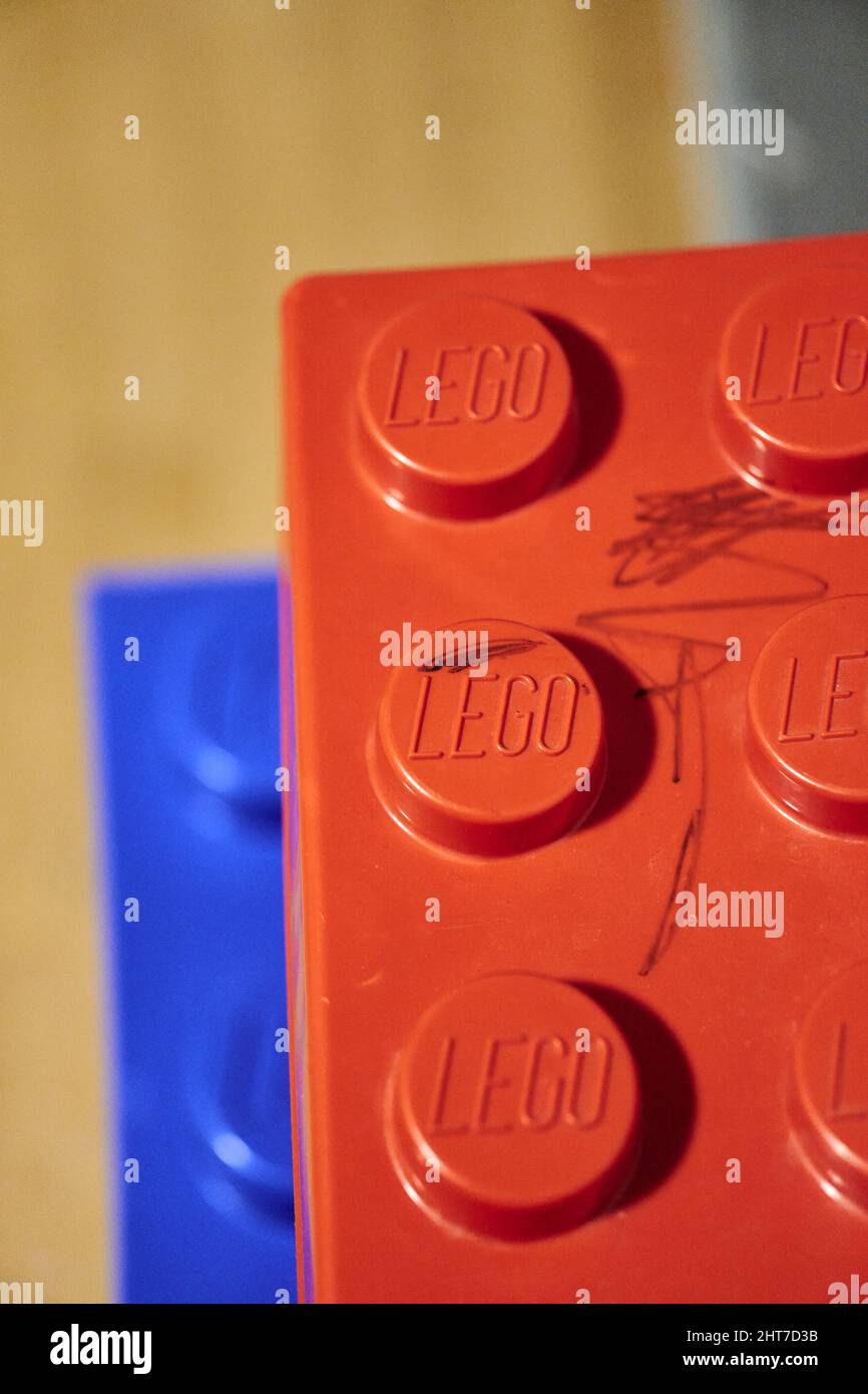 Vertical shot of red and blue legos with scribbles on them on a blurry ...