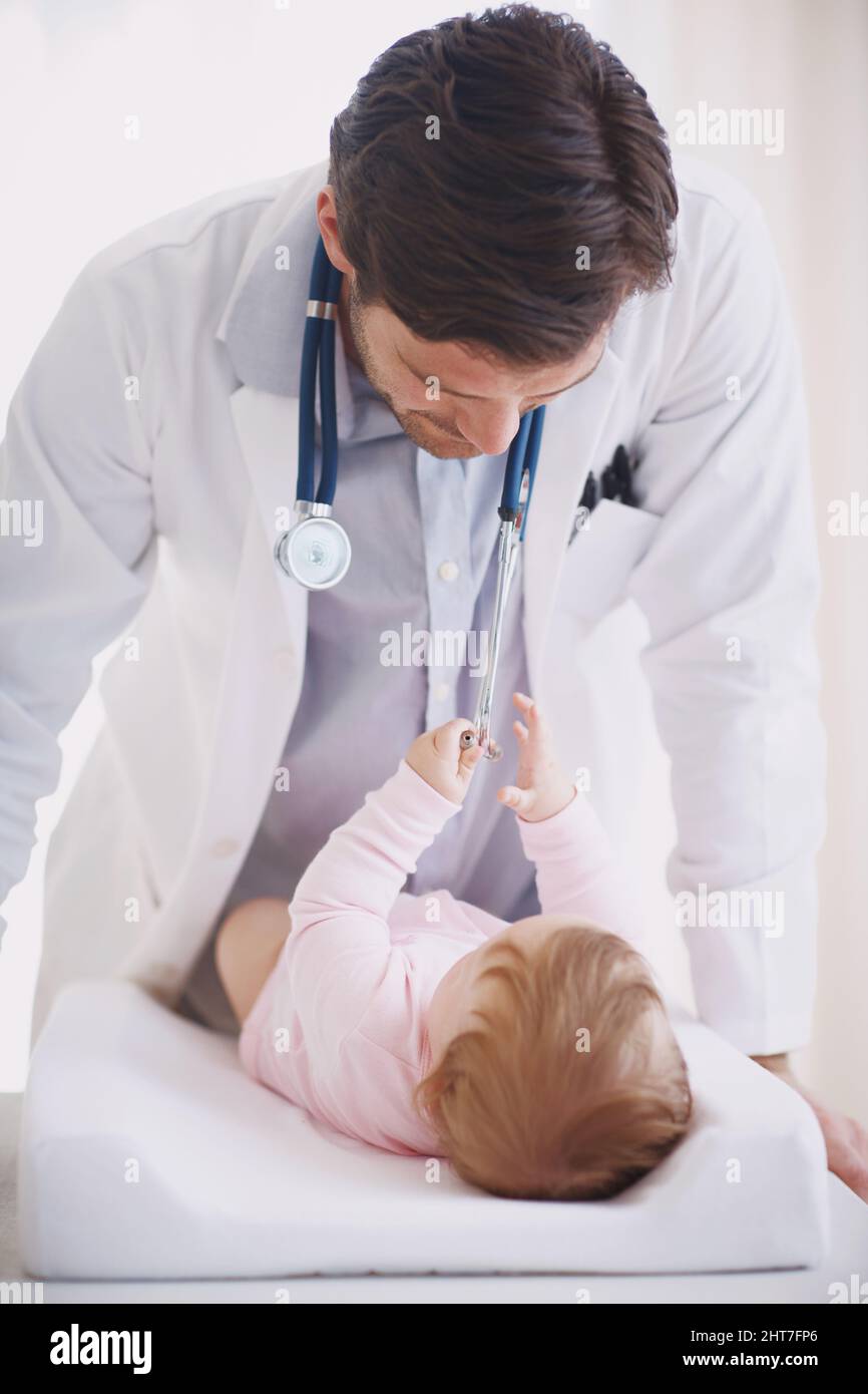 Meeting his little patient. A male doctor standing by an infant patient ...