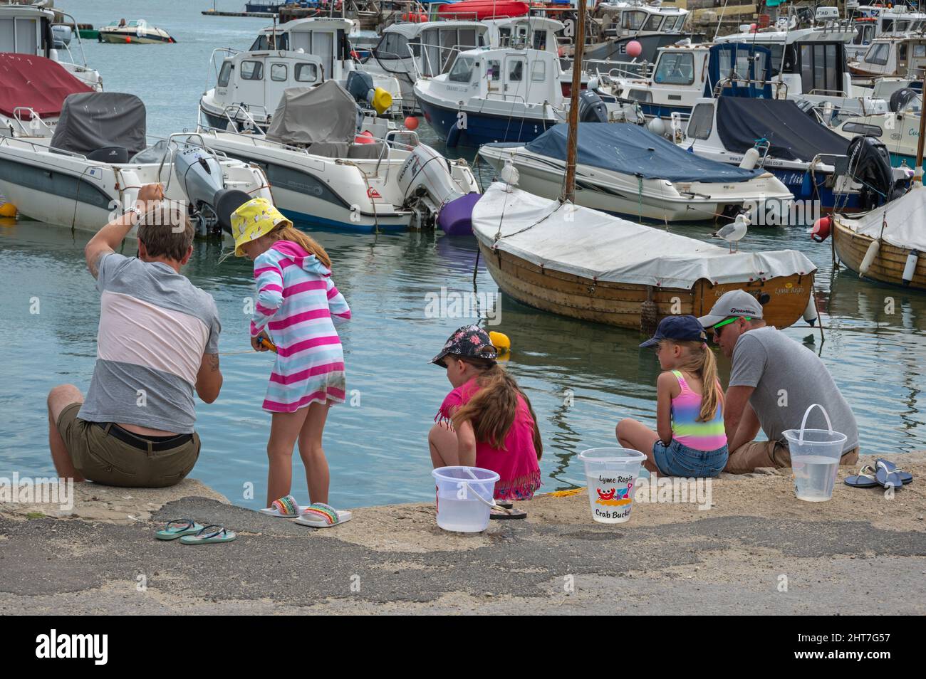 Holiday Makers fishing for crabs from the harbour walls of the Cobb at ...