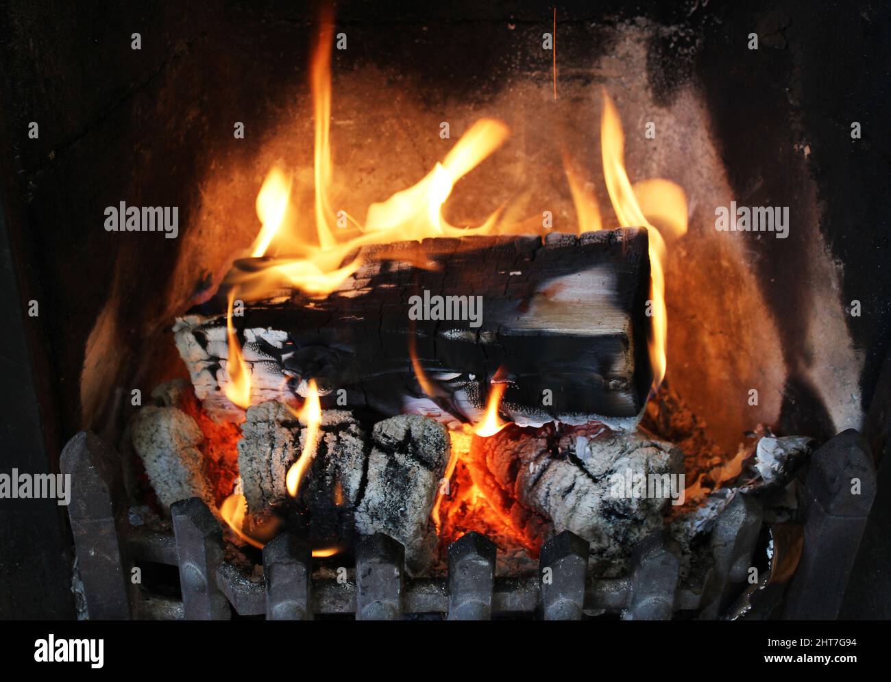 A burning log on an indoor living room fire on hor ashes Stock Photo ...
