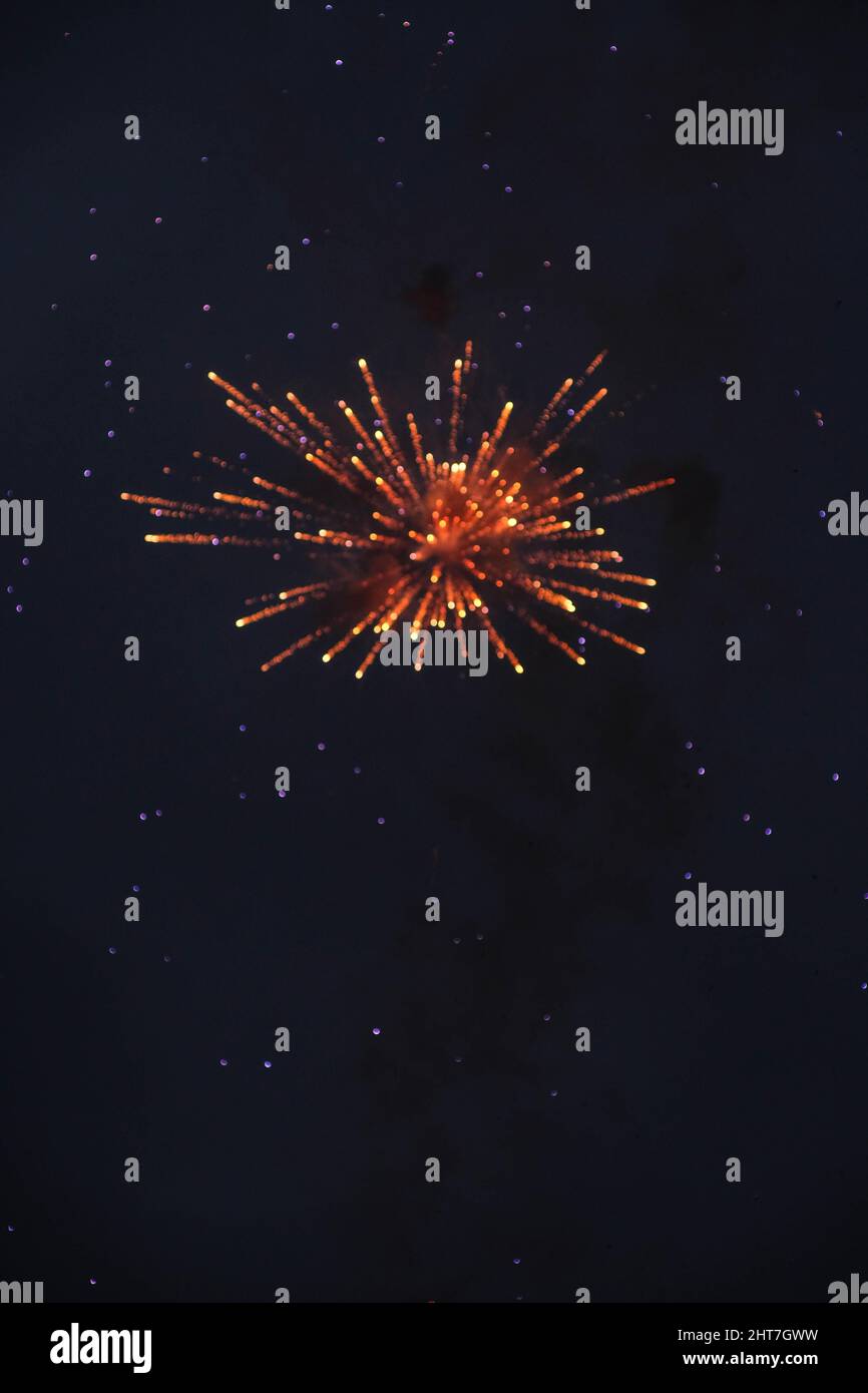 Low angle shot festive fireworks bursting in night sky with red sparks ...