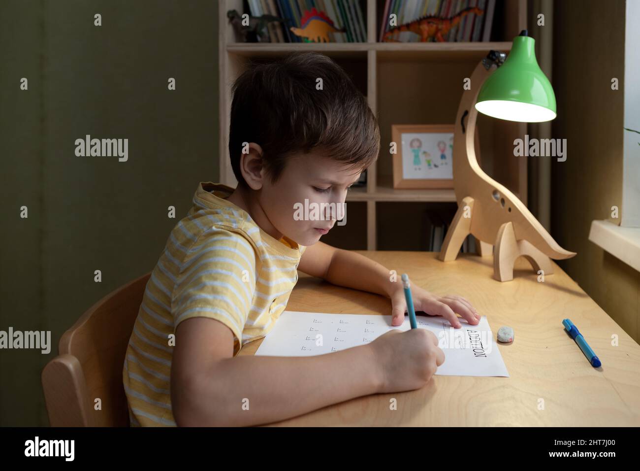 A schoolboy doing math lesson sitting at desk in the children room ...