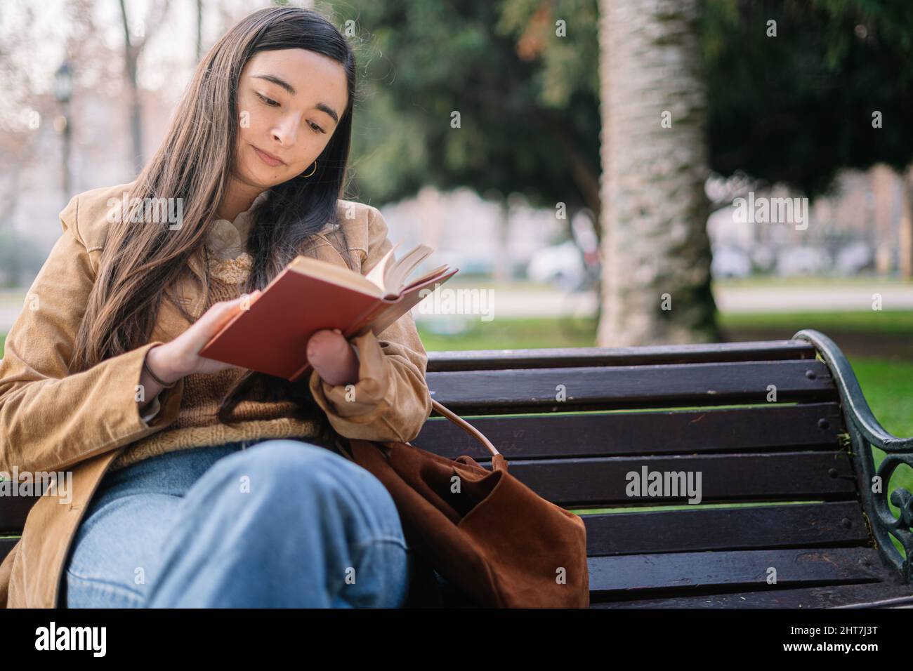 Hispanic woman disabled person in her hand reading a book on a bench ...