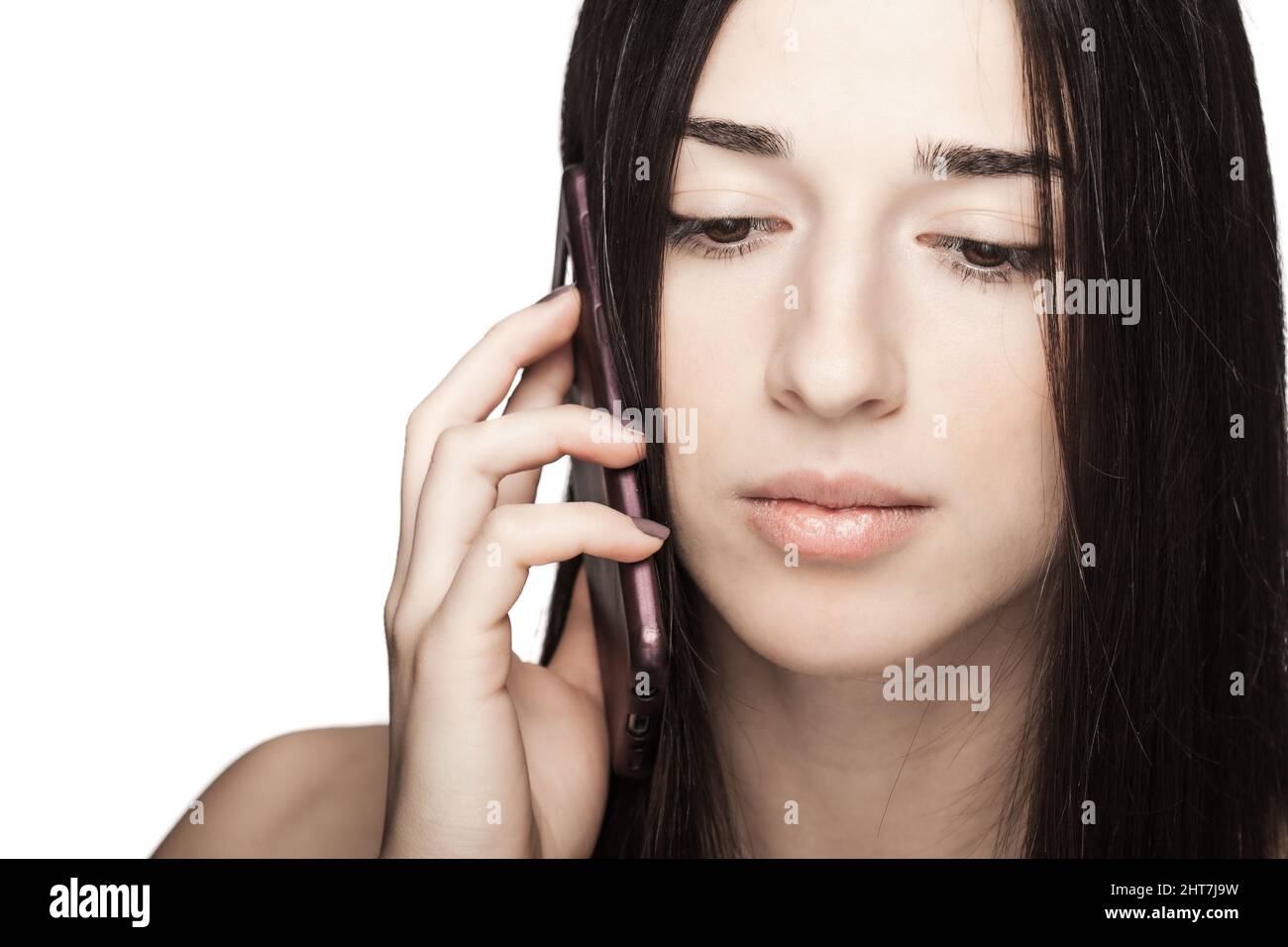 studio portrait of a beautiful brunette girl using phone against white ...