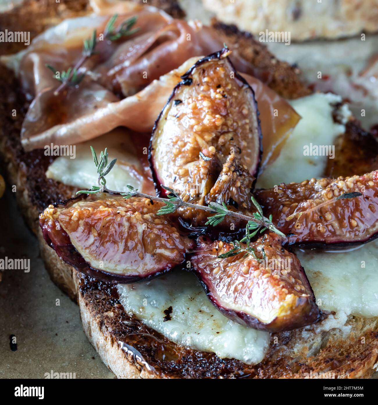 A roasted fig on toasted fig and prosciutto tartine topped with thyme ...