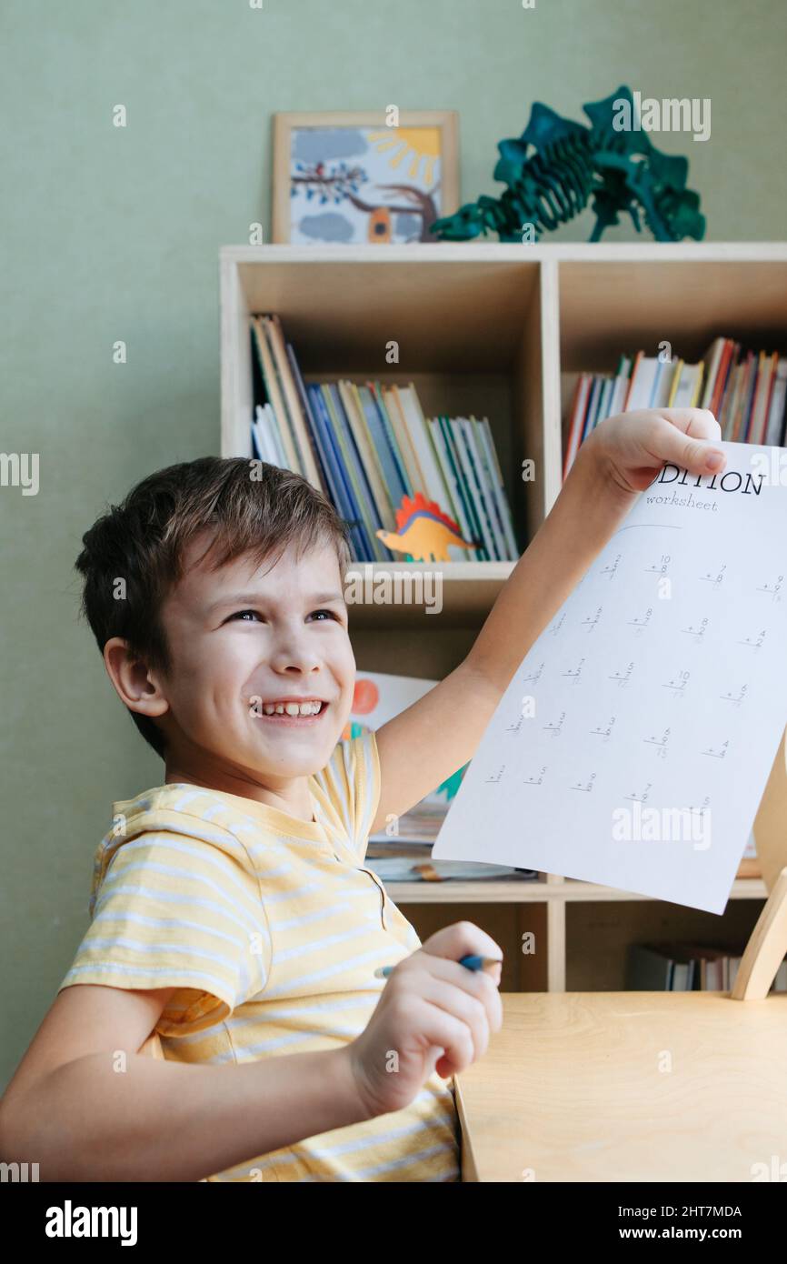 A schoolboy doing math lesson sitting at desk in the children room ...