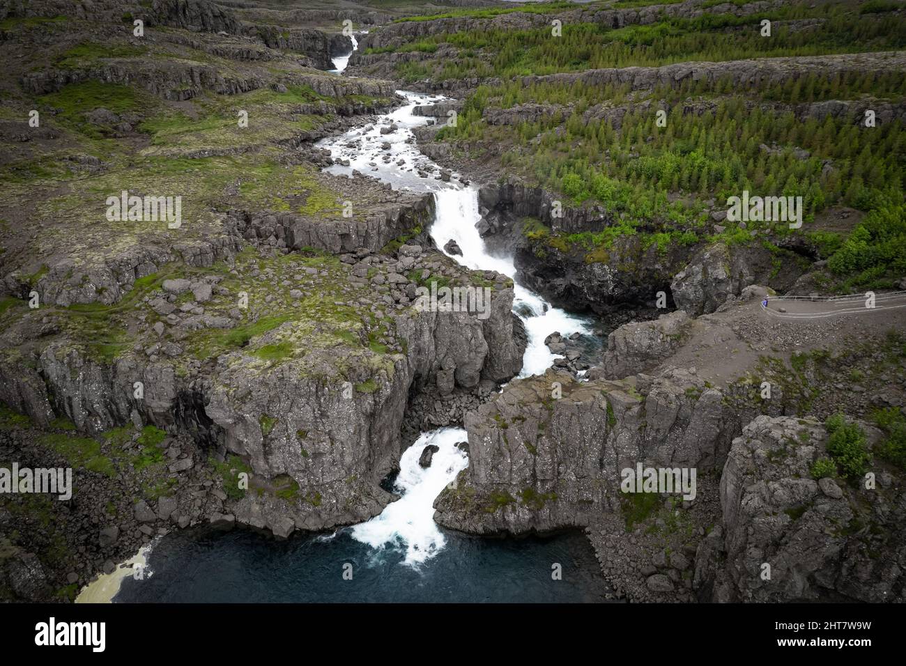 High-angle shot of cliffs and a narrow water stream flowing and falling ...