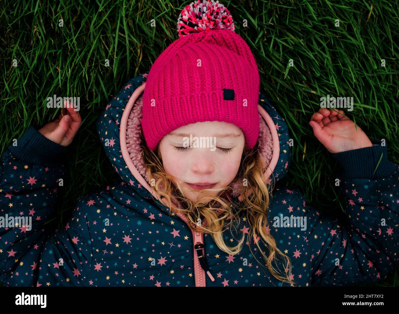 girl calmly laying in the grass relaxing with her eyes closed Stock ...