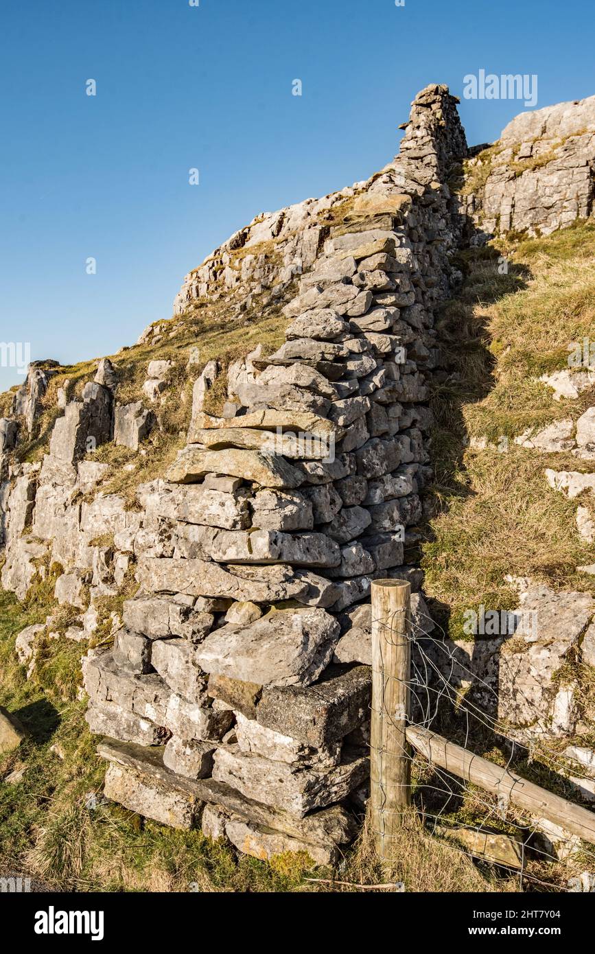 A drystone wall,itself built from limestone, follows the rising ground ...
