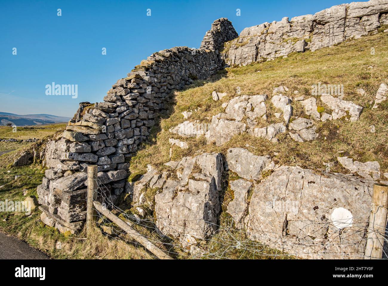A drystone wall,itself built from limestone, follows the rising ground ...