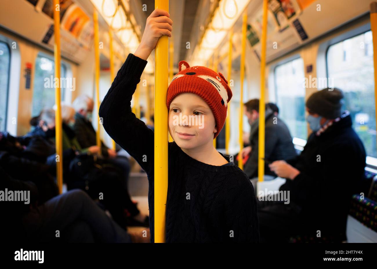 boy standing on a train in London surrounded by passengers Stock Photo ...