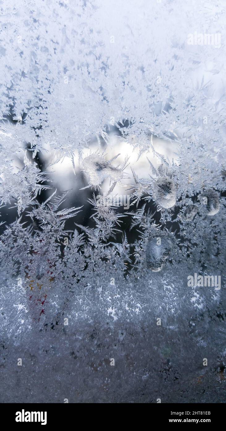 Vertical background of a frozen window with beautiful snowflake ...