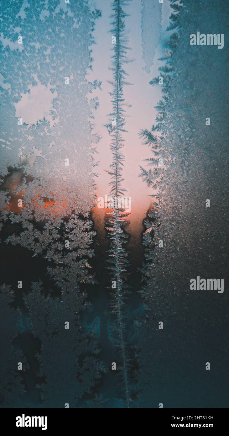 Vertical background of a frozen window with beautiful snowflake ...