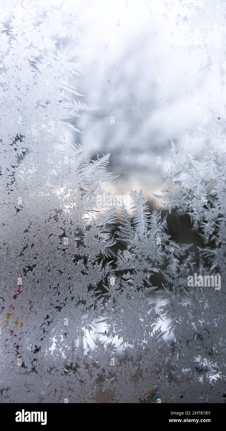 Vertical background of a frozen window with beautiful snowflake ...