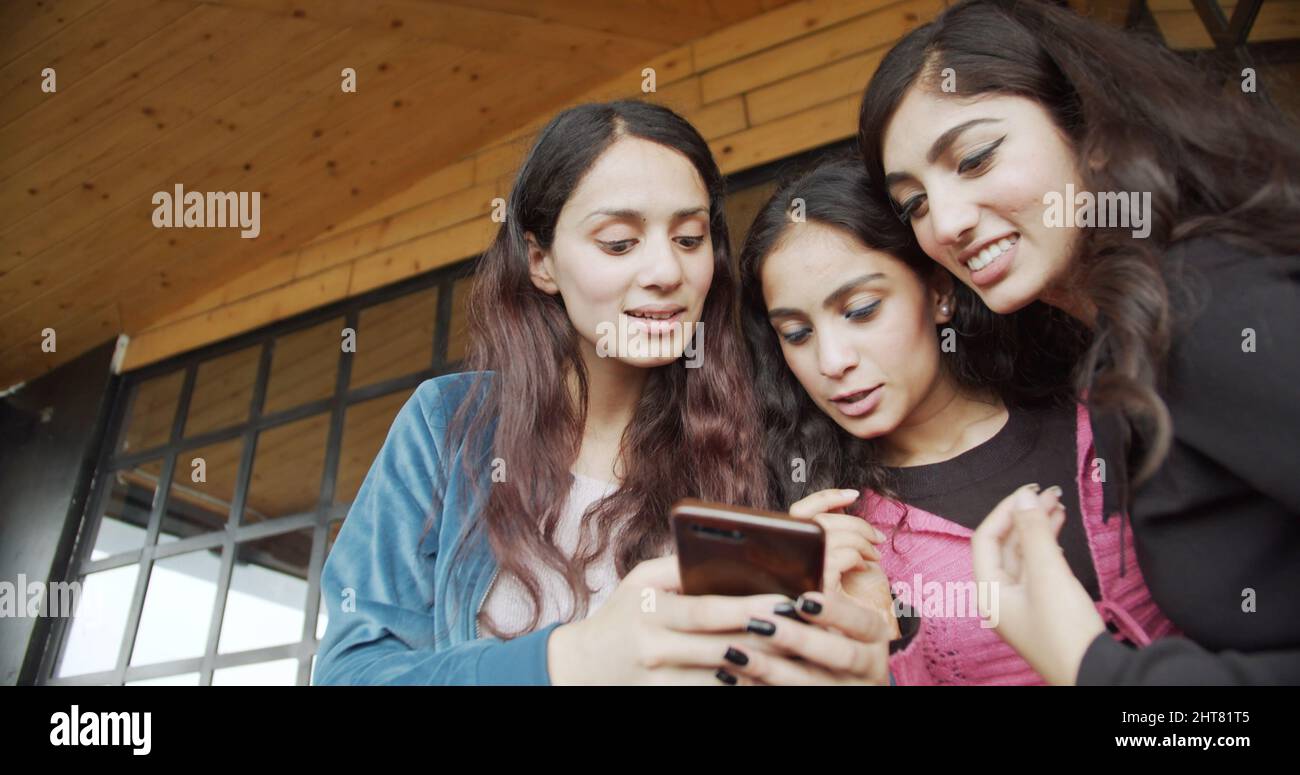 Young South Asian ladies from India watching something on a smartphone ...
