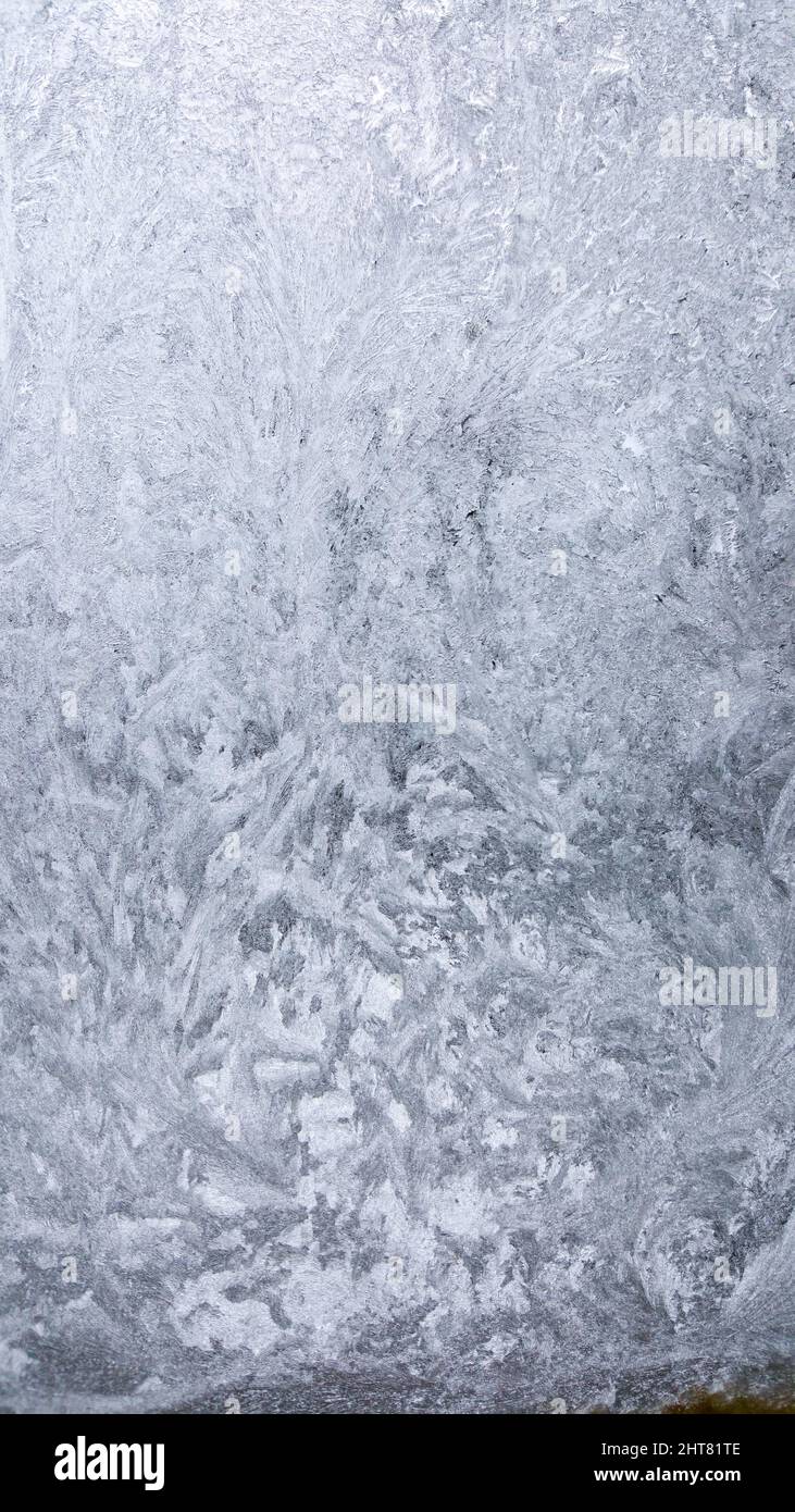 Vertical background of a frozen window with beautiful snowflake ...