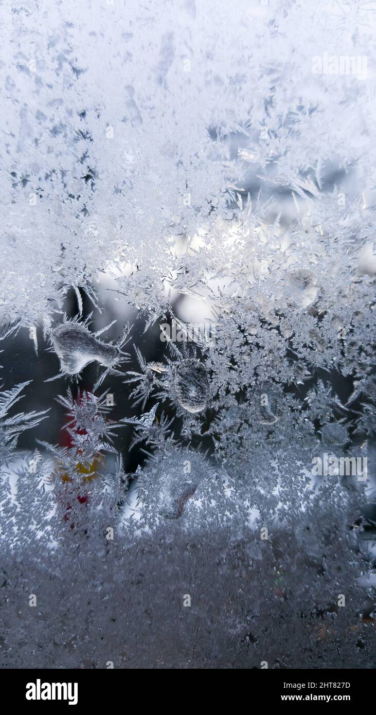 Vertical background of a frozen window with beautiful snowflake ...