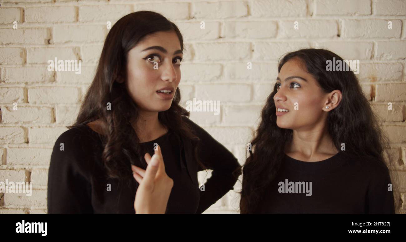 Couple of Indian females talking to each other with serious and smiling ...