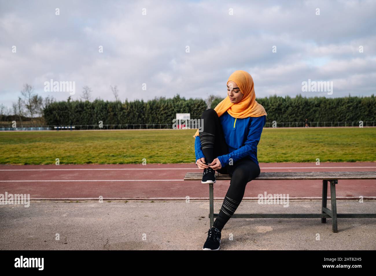Ethnic woman sitting on bench and tying sneakers before running Stock ...