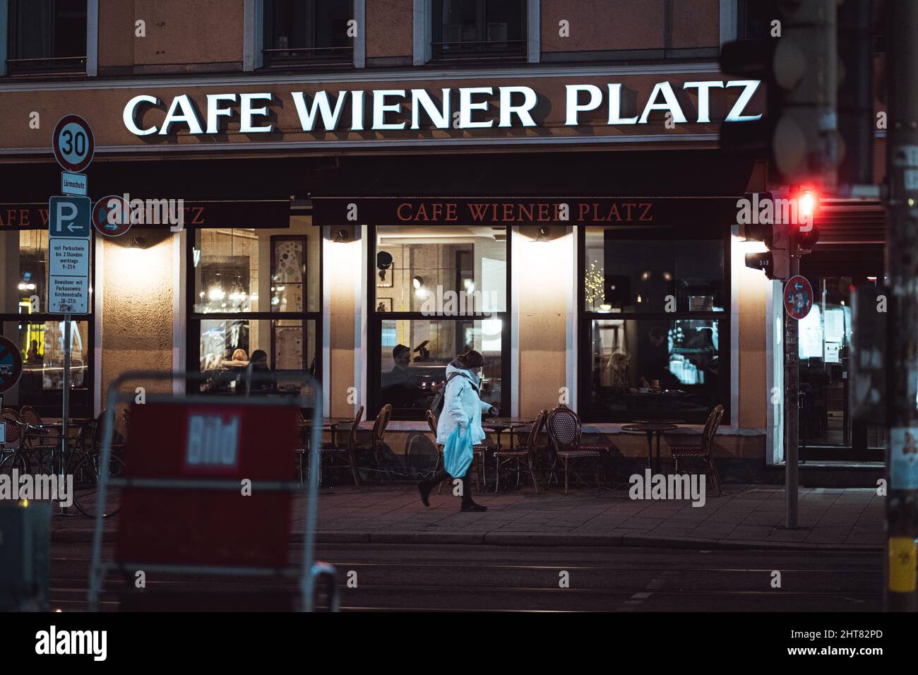 Photo of Cafe Wiener Platz in Munich at night, an old woman walks past ...