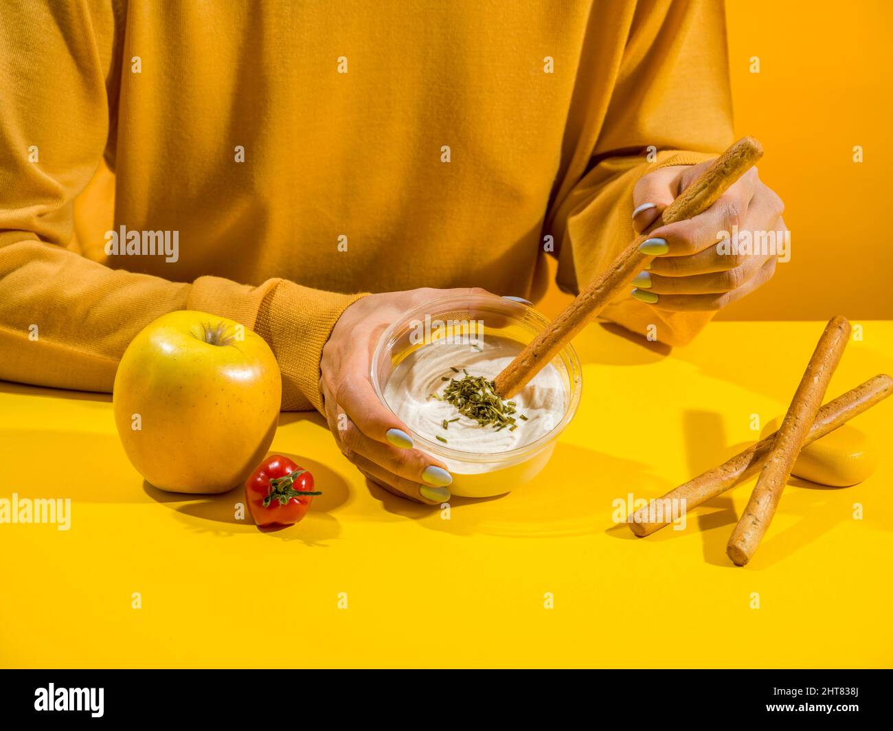 Girl in yellow eating crackers and cream cheese Stock Photo - Alamy