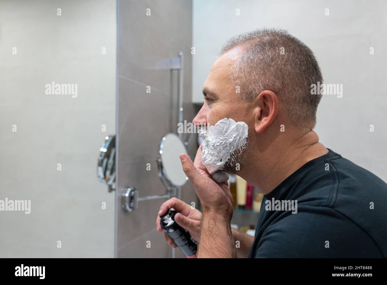 Mature handsome man applying shaving foam on his face to cut off his ...