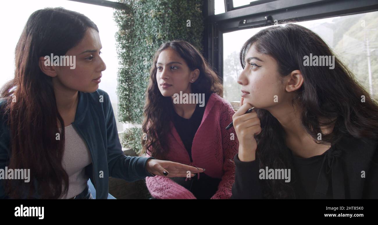 Group of Indian young female talking to each other with serious faces ...