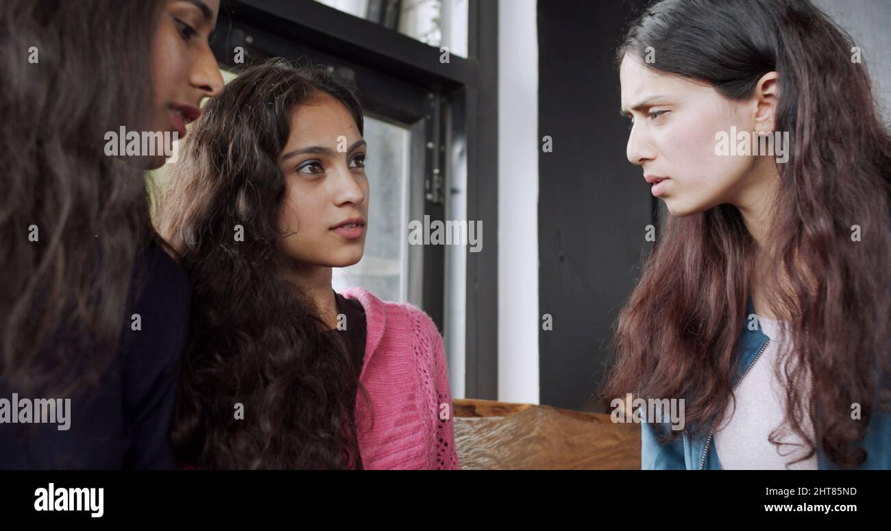 Group of Indian young female talking to each other with serious faces ...