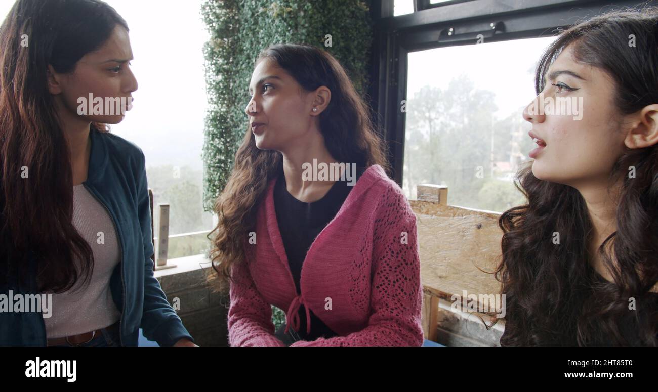 Group of Indian young female talking to each other with serious faces ...