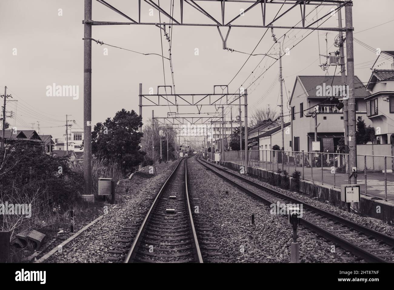 Grayscale shot of railway tracks in Kyoto, Japan with buildings on the ...
