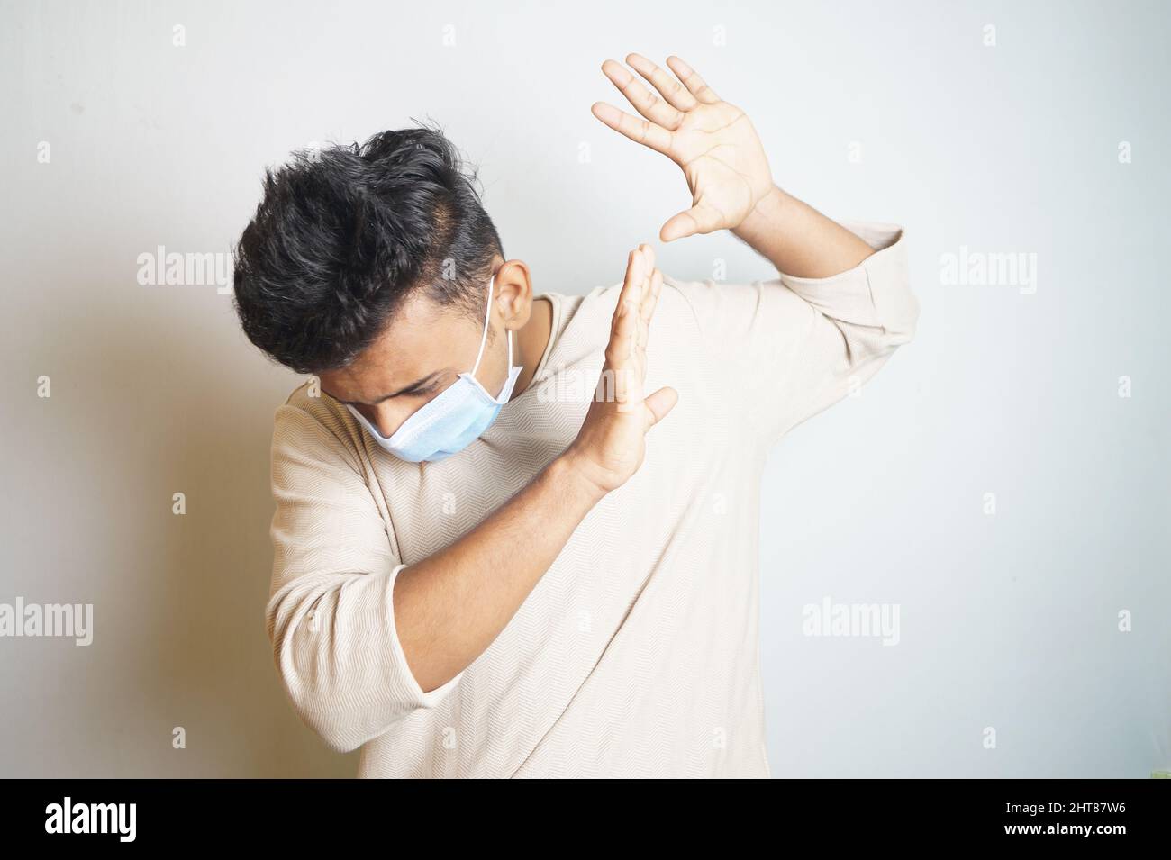 Young man holding his hands up wearing a surgical mask on a white ...