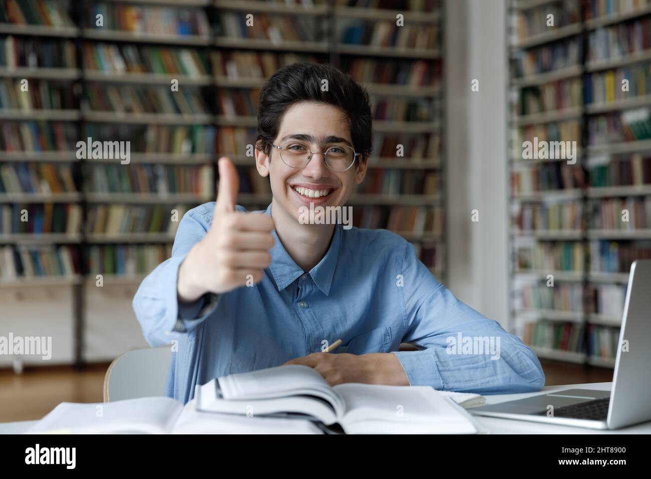 Portrait of happy millennial male student studying in library Stock ...