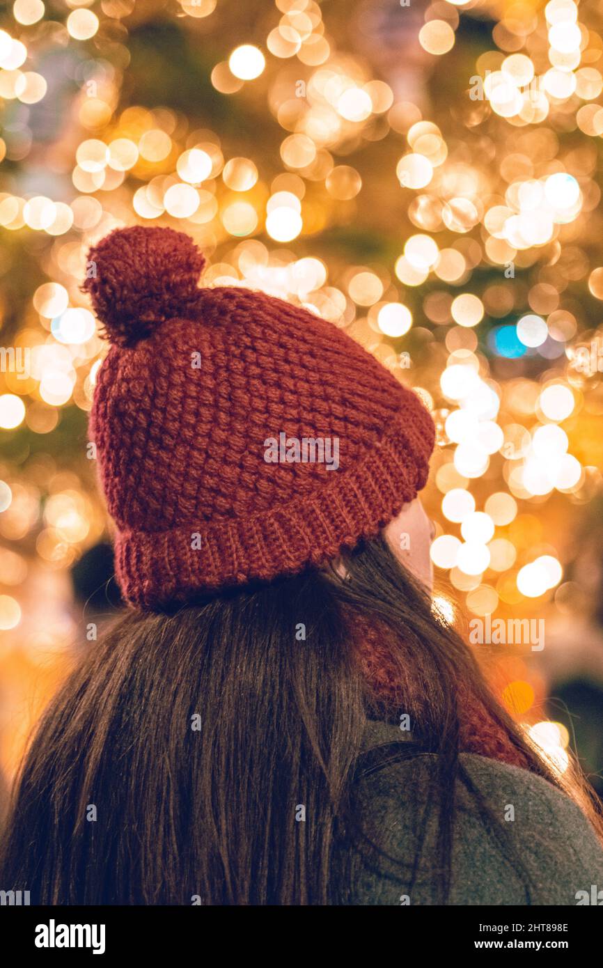 Vertical rear view of a girl wearing a red hat and a scarf standing ...