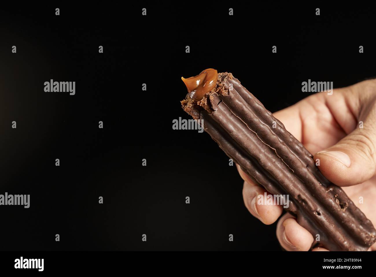 Close up shot of a hand offering churro filled with dulce de leche ...