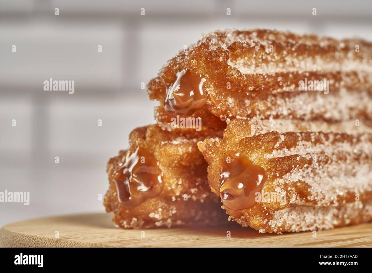 Close up shot of three churros filled with dulce de leche caramel on a ...