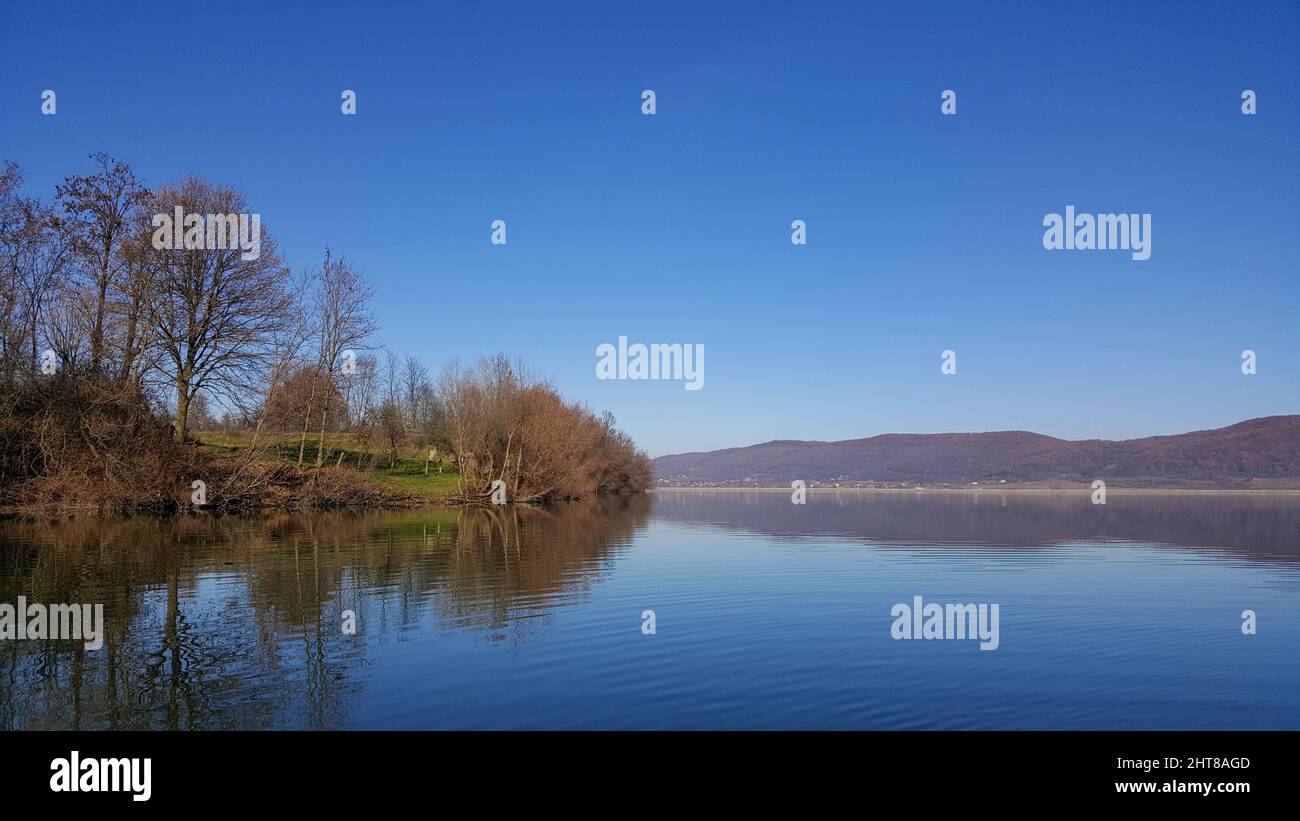 Landscape with a huge lake with reed and rush, rocky mountains and high ...