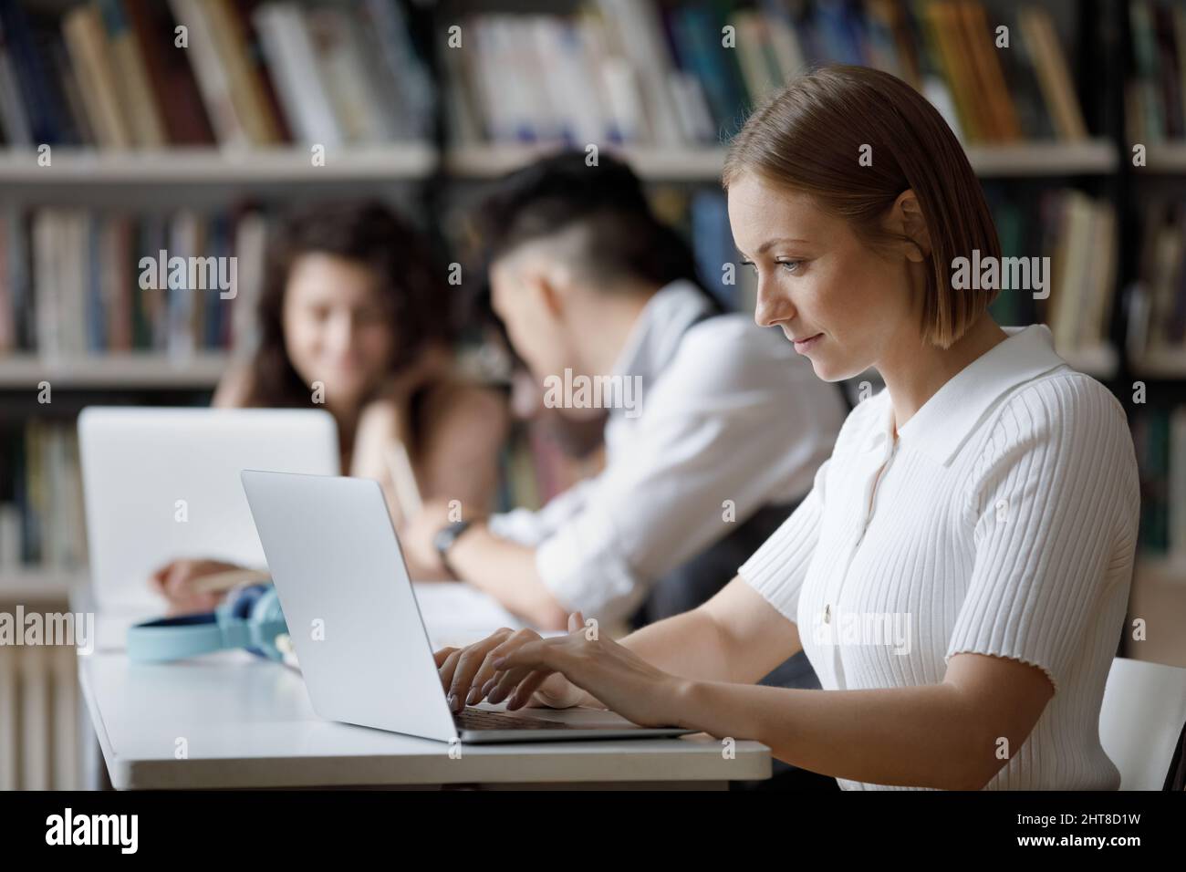 Happy focused smart female student working on computer in library Stock ...