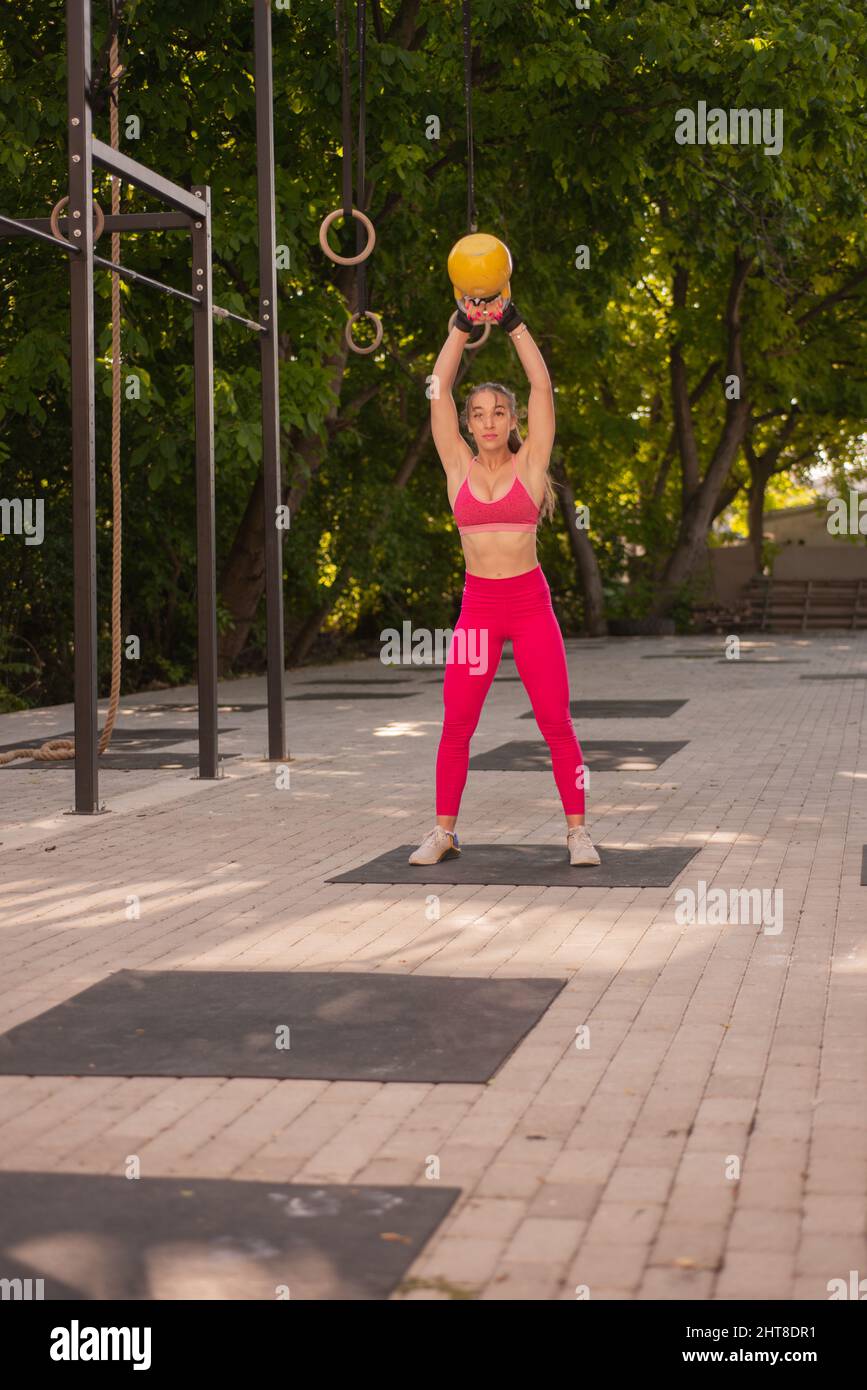 Attractive and beautiful fit girl is doing a weight lifting exercise ...