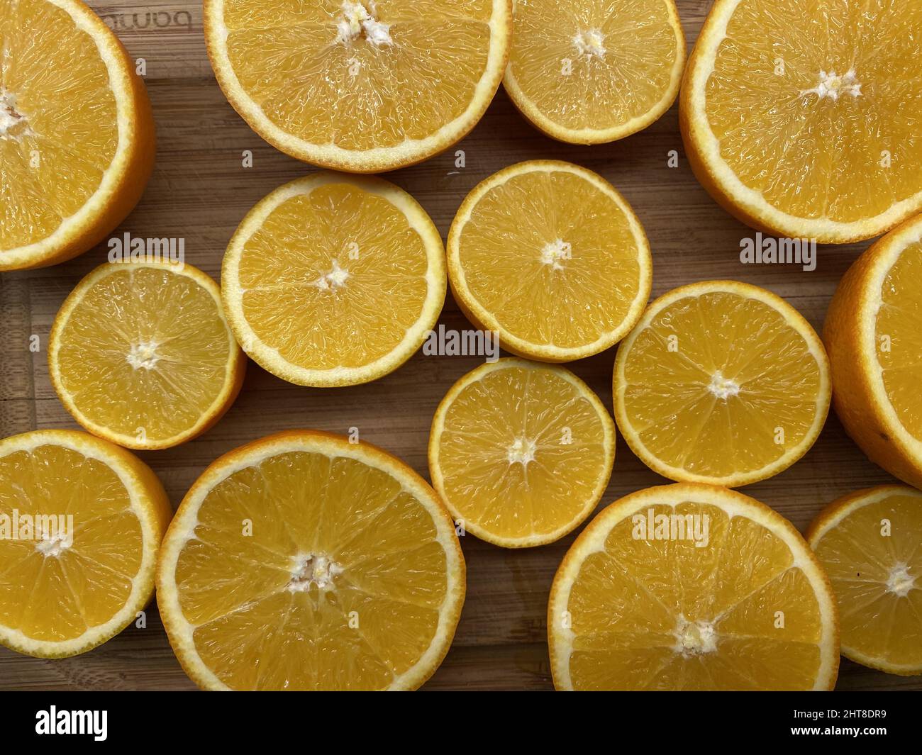 Vertical shot of freshly sliced seedless oranges on a wooden surface ...