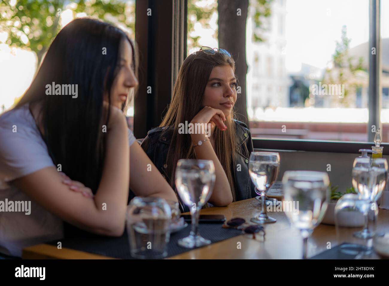 Two beautiful and attractive girl friends are looking and listening to ...